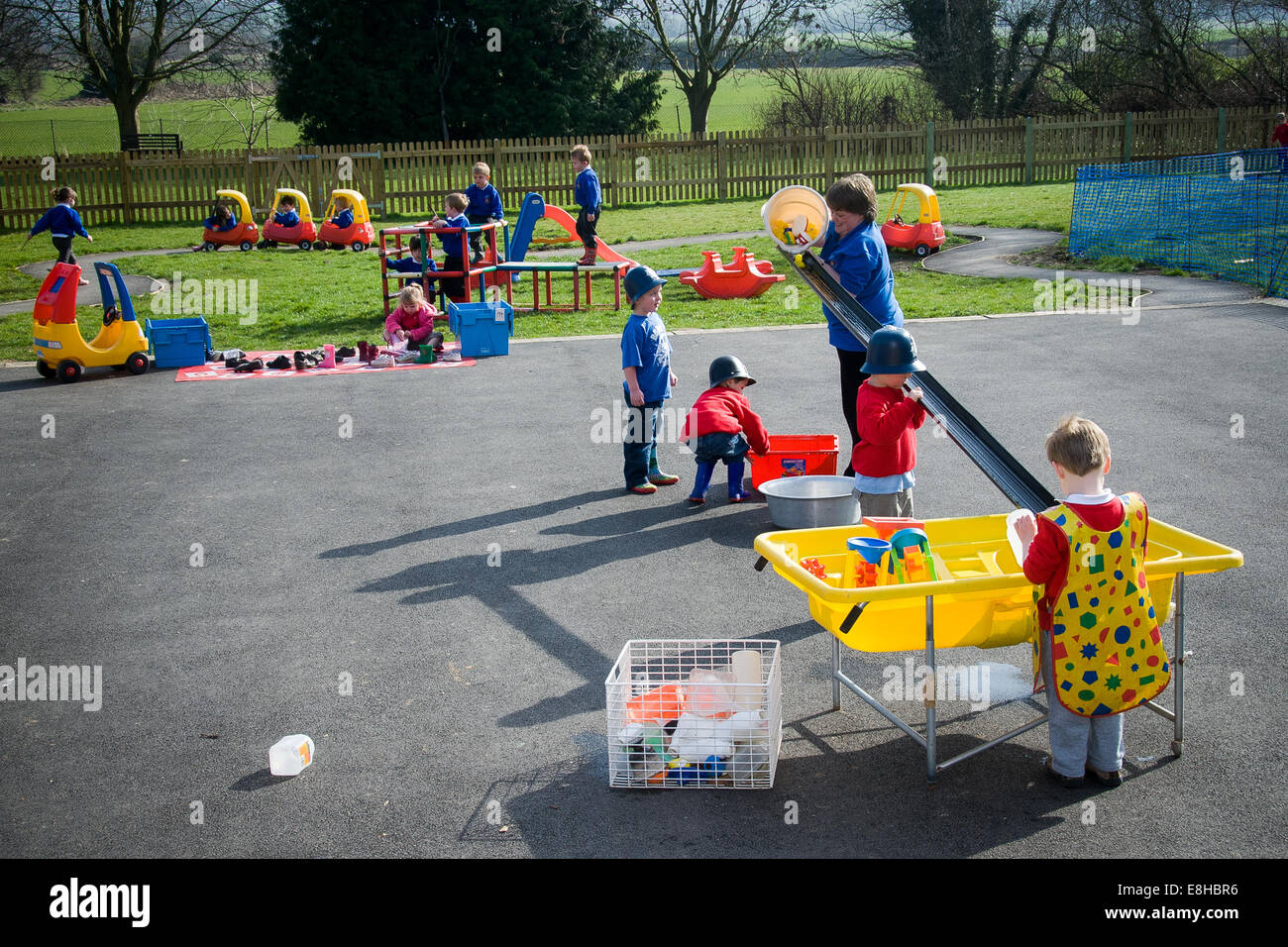 Reception children playing outside school in playground with teaching ...