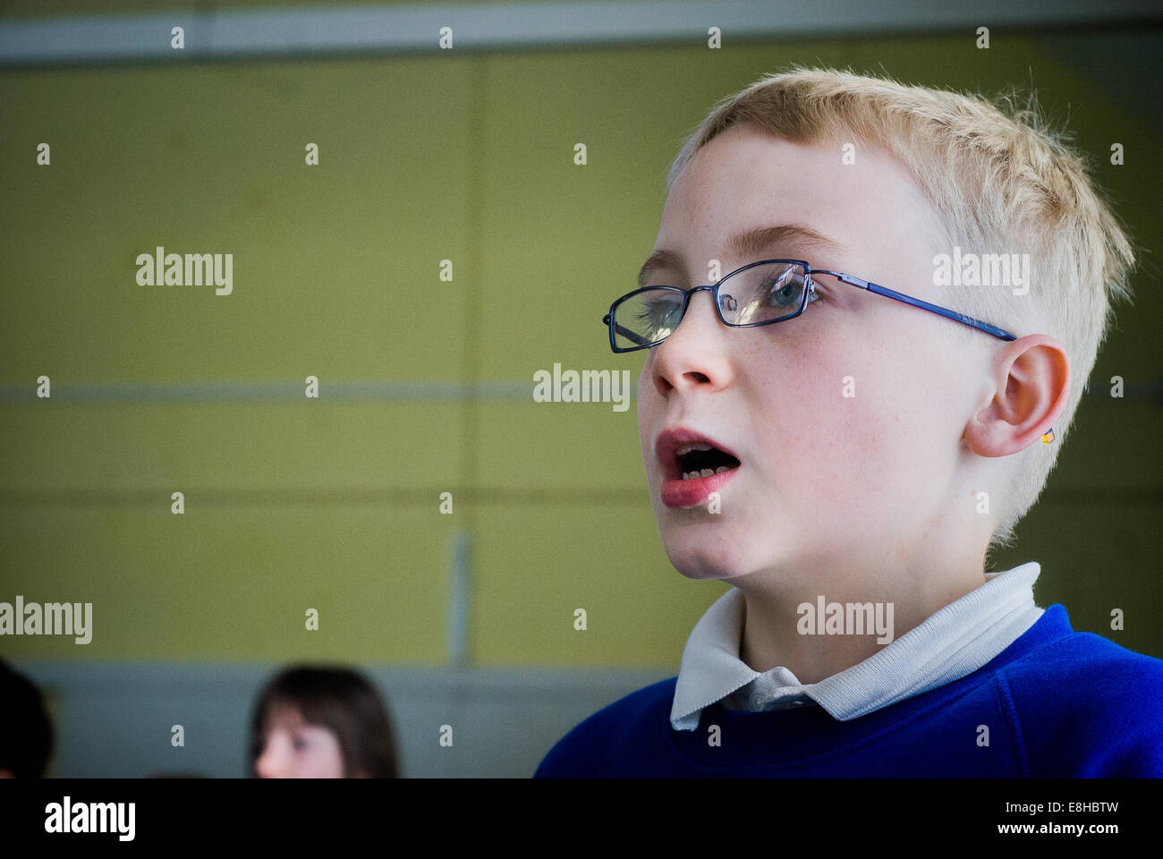 Boy with glasses singing at a primary school assembly, UK Stock Photo ...