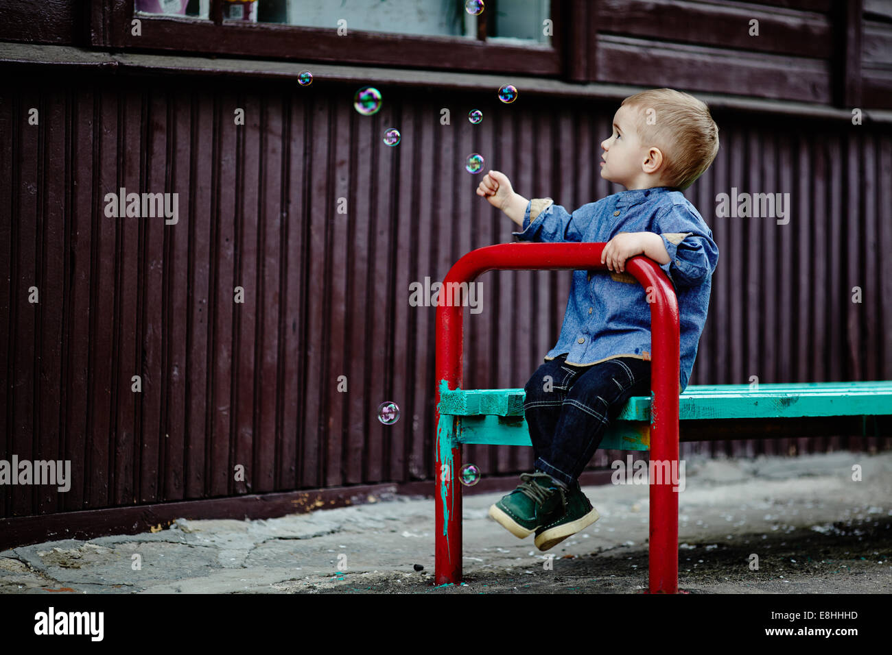 little boy catches bubbles sitting on bench Stock Photo - Alamy