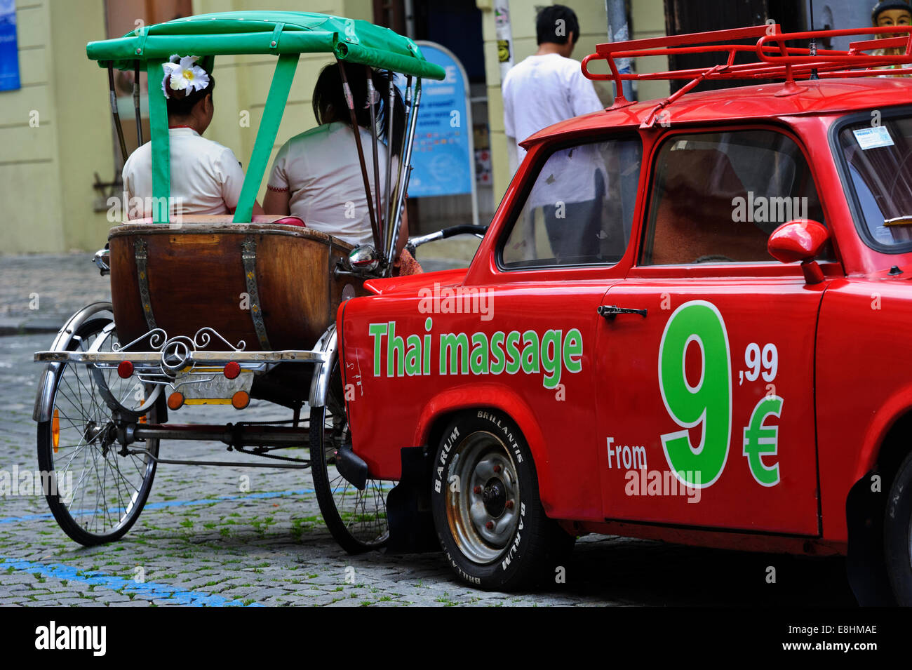 A red car and a rickshaw with two thai female outside Thai Massage parlour in the City of Prague ...