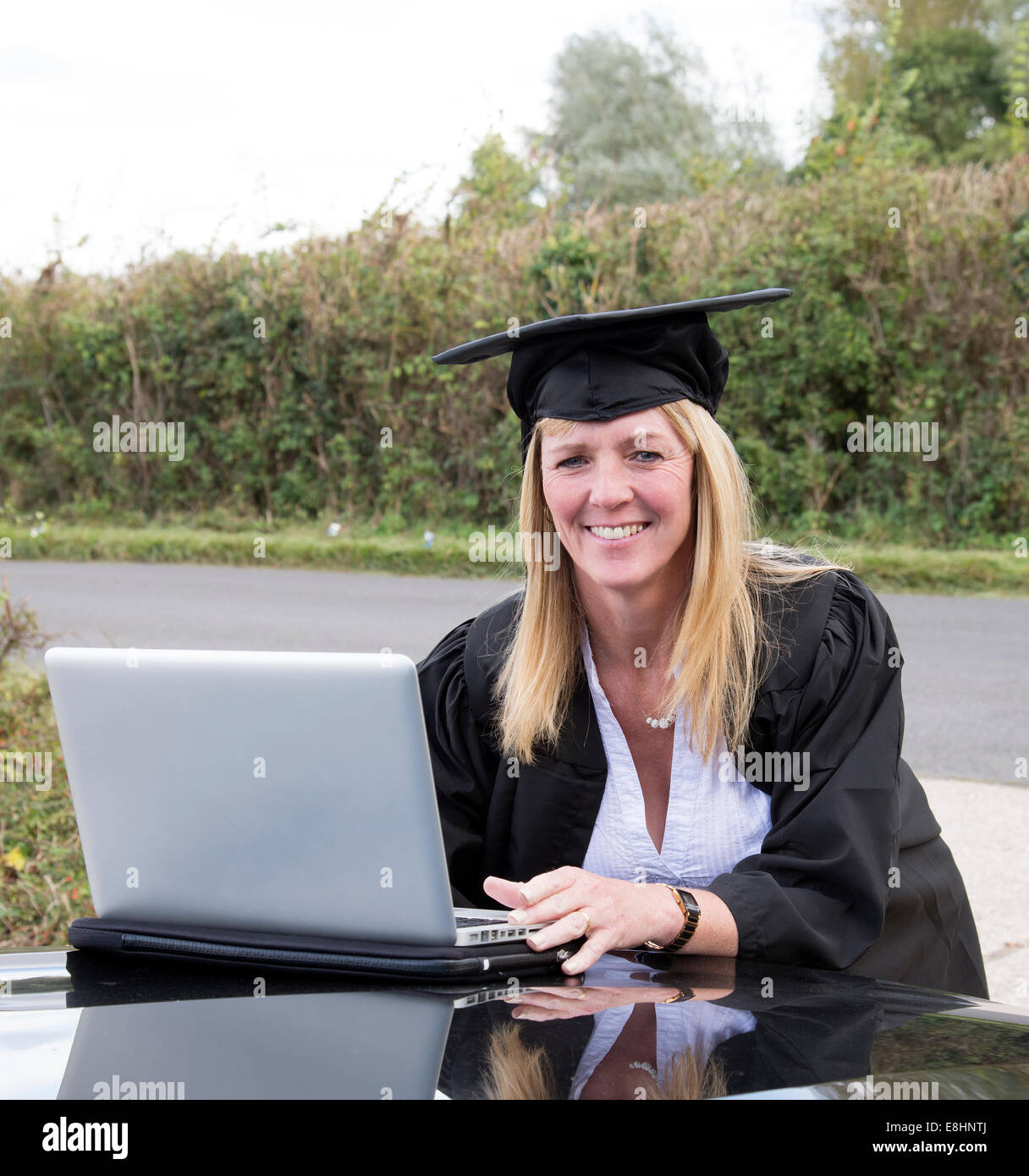 Mature university student using a laptop computer on car bonnet Stock ...