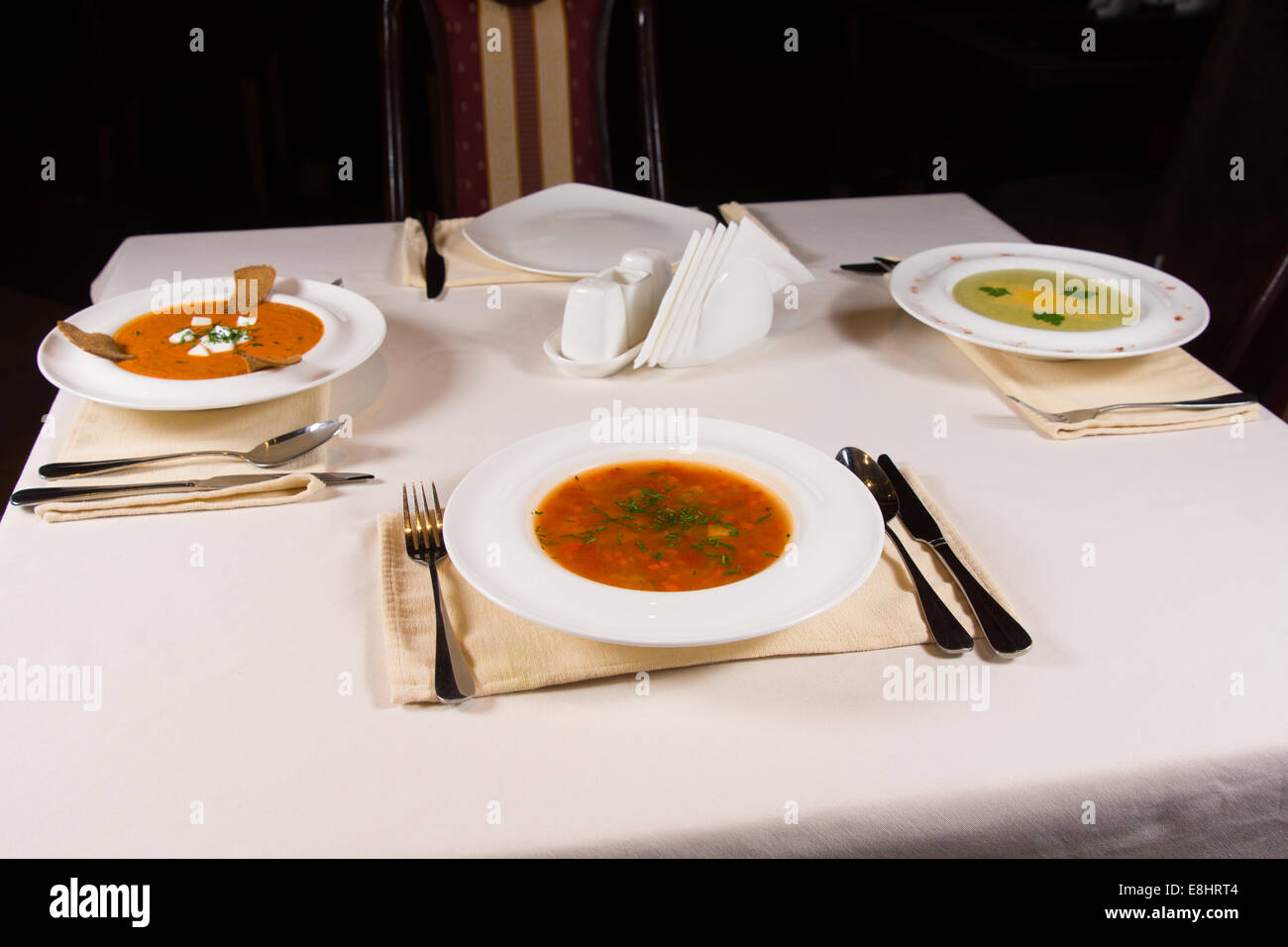 Table set with three different bowls of gourmet vegetable soup with ...