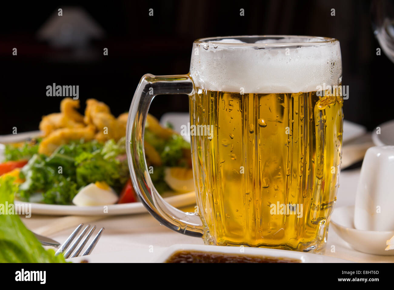 Mug of refreshing cold beer with a good frothy head served at table ...