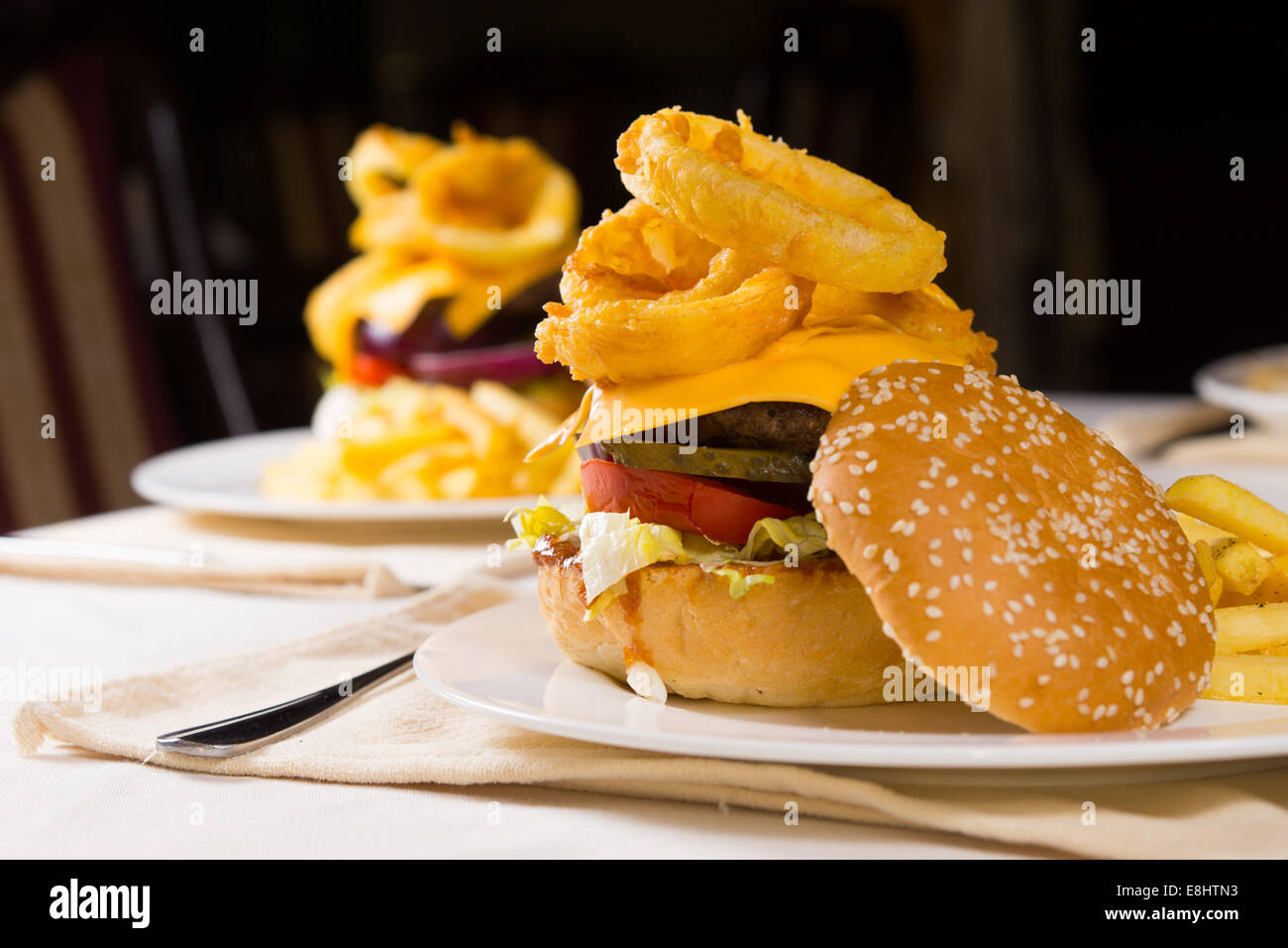 Gourmet Cheeseburgers Piled High with Toppings on Plates on Restuarant ...