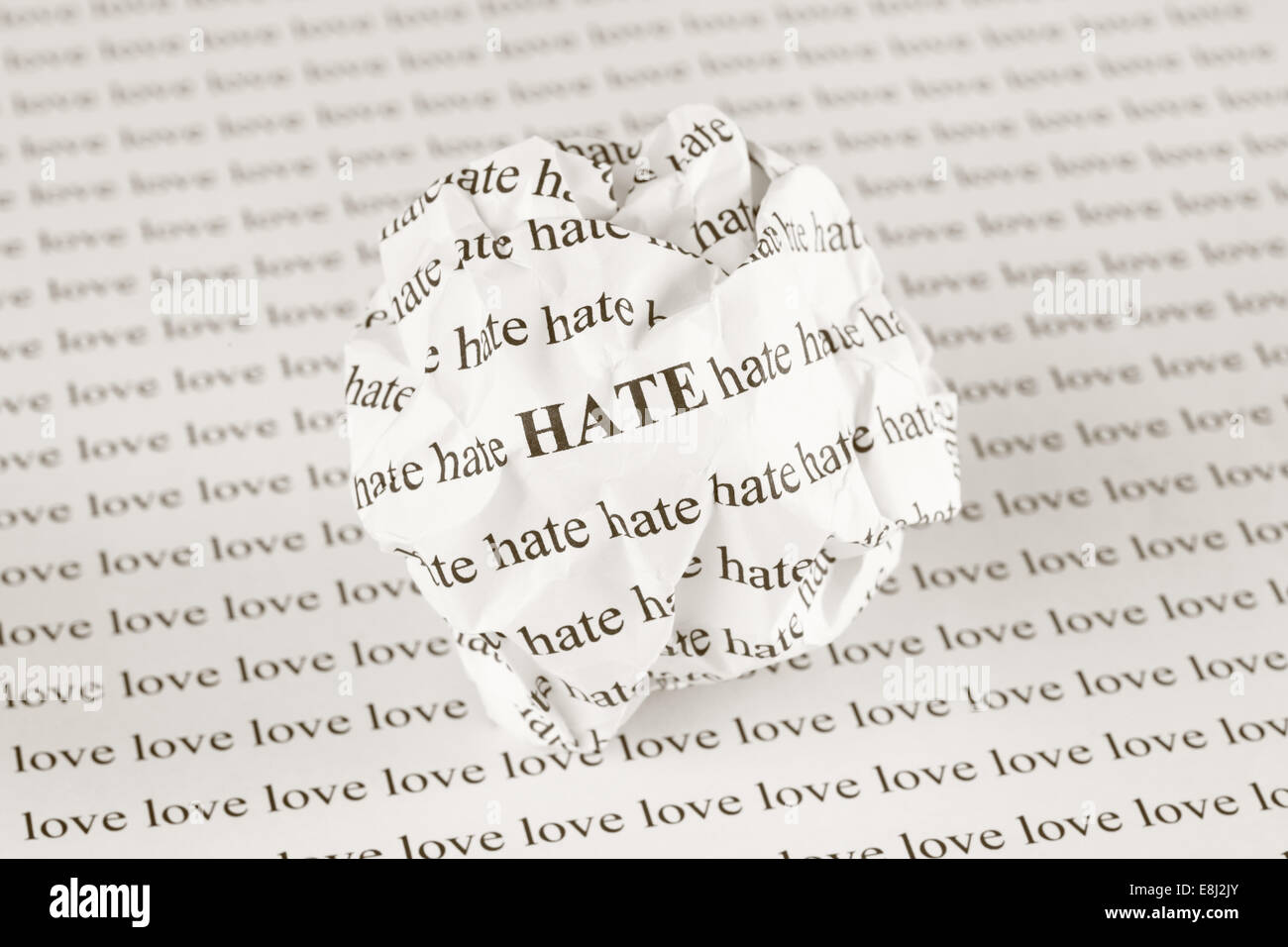 Crumpled paper ball with words "Hate" on background with words "Love ...