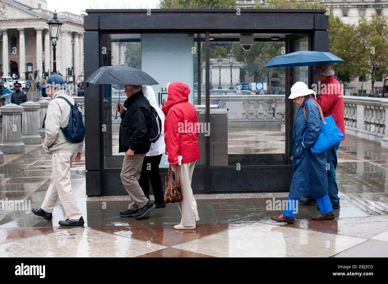 Tourists in wet weather by lift in Trafalgar Square, London, UK Stock ...