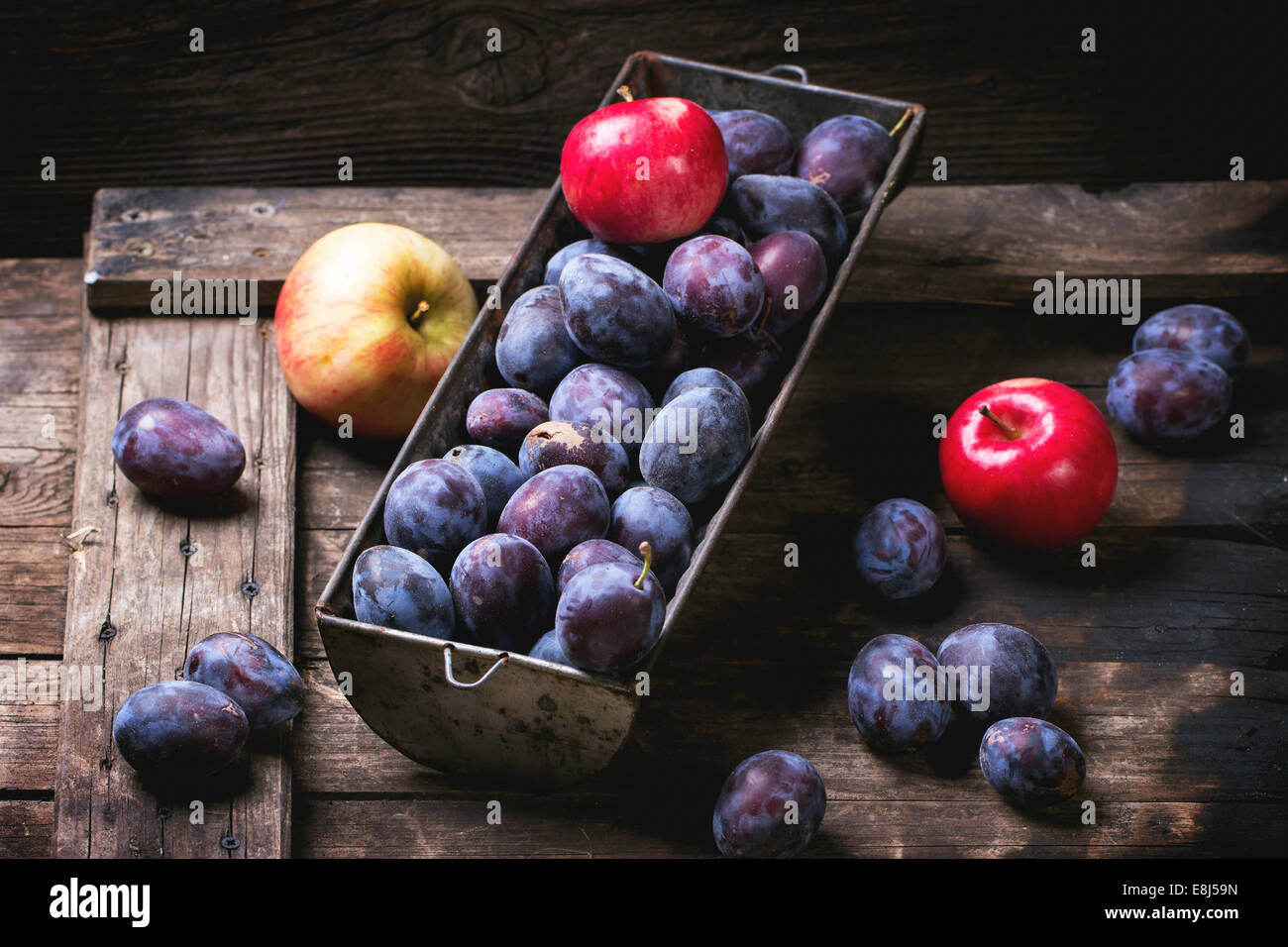 Whole and sliced plums over old wooden table Stock Photo - Alamy