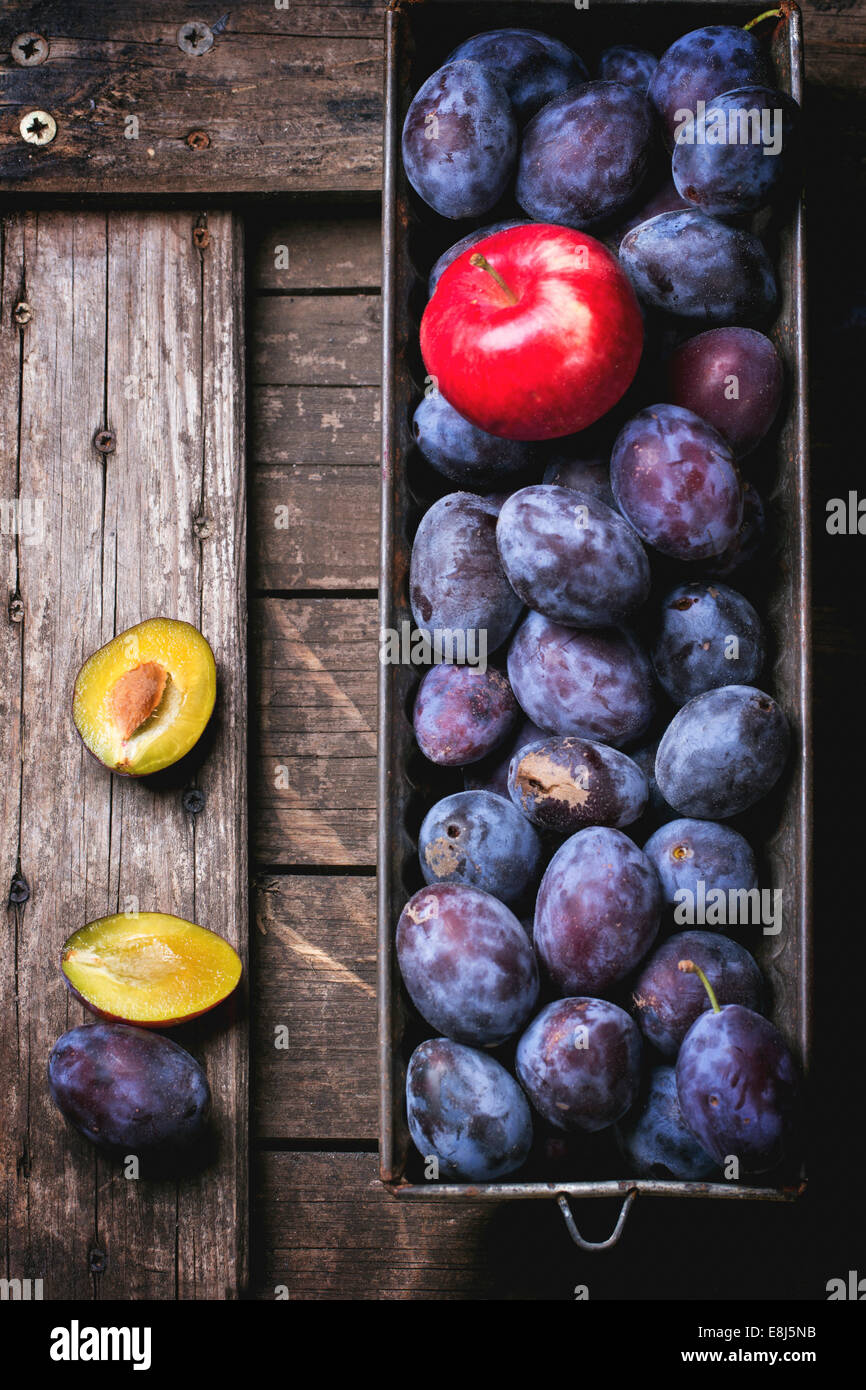 Whole and sliced plums over old wooden table Stock Photo - Alamy