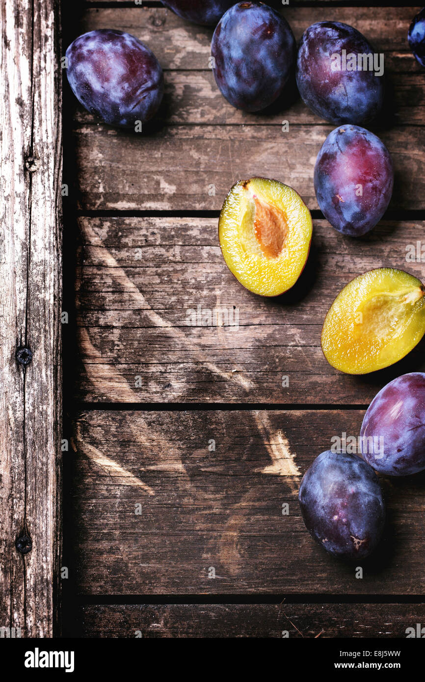 Whole and sliced plums over old wooden table Stock Photo - Alamy