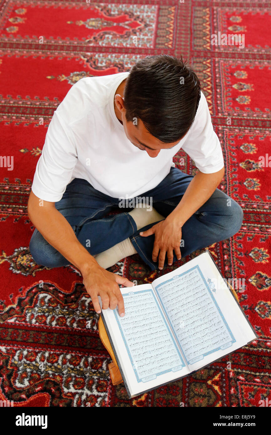 Young man reading the Koran in Imam Hussein mosque, Baku Stock Photo ...