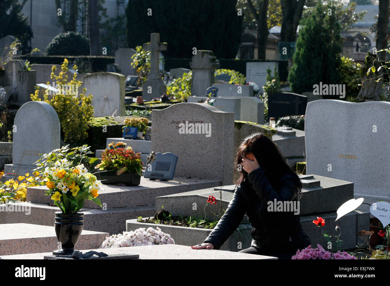 Woman praying at a grave in a cemetery Stock Photo - Alamy