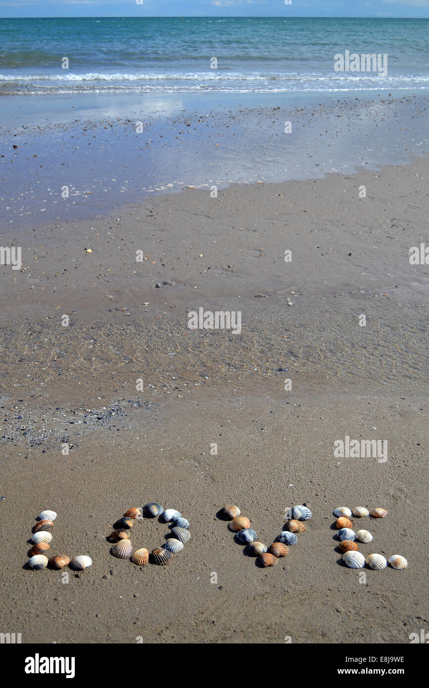Love written using shells on the beach Stock Photo - Alamy