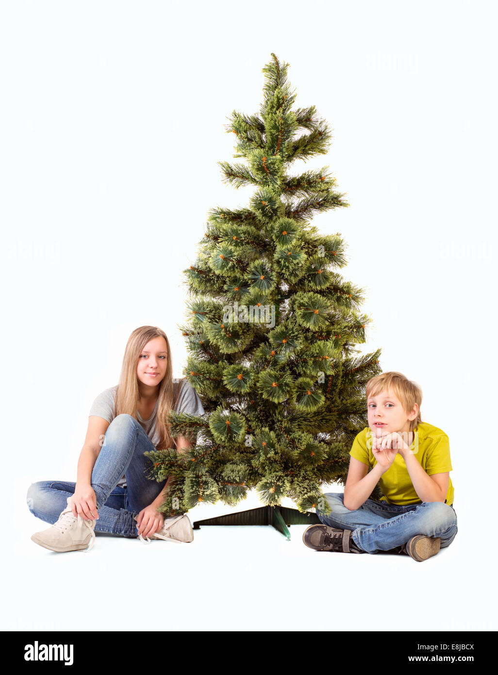 Boy and girl sitting under the Christmas Tree Stock Photo - Alamy