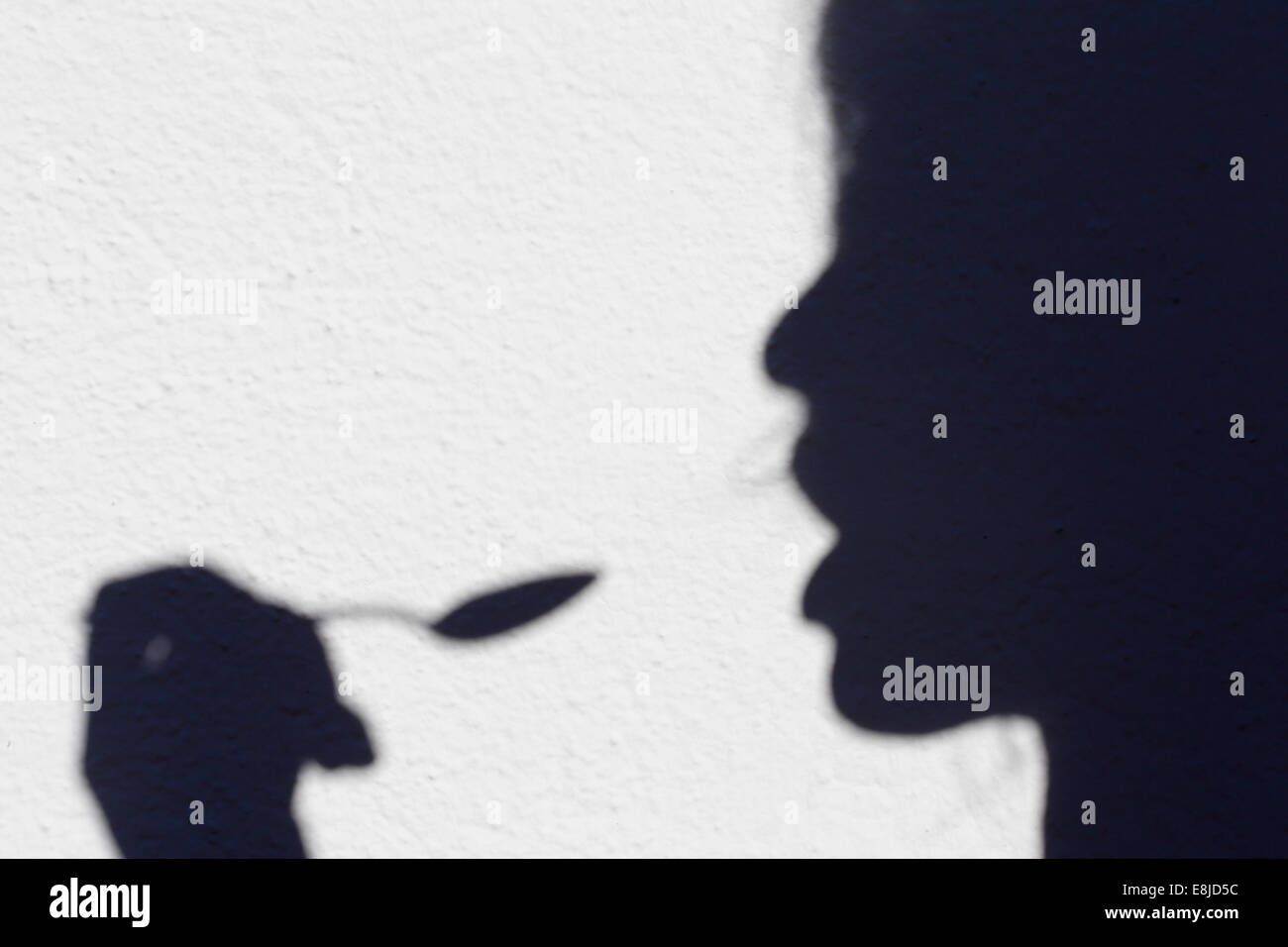 Shadow of a woman eating with a spoon Stock Photo - Alamy