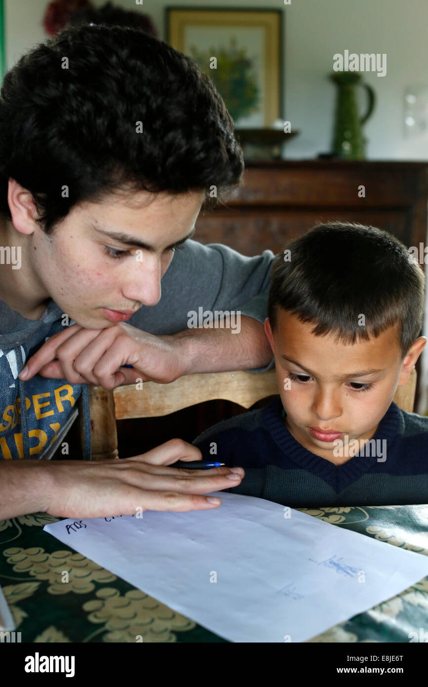 Teenager helping his brother with his homework Stock Photo - Alamy