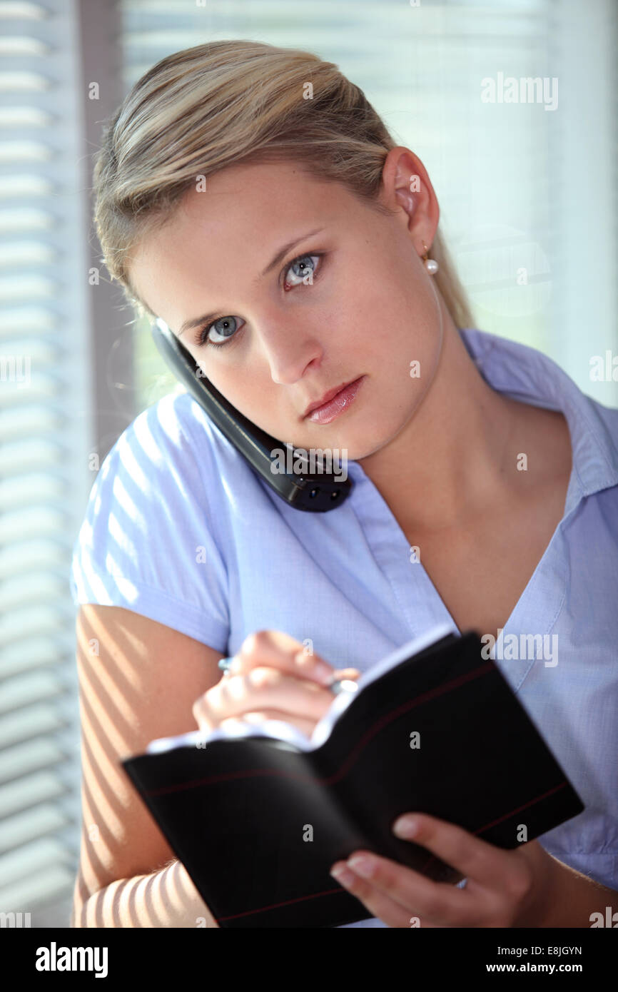 Blond secretary writing in diary Stock Photo - Alamy
