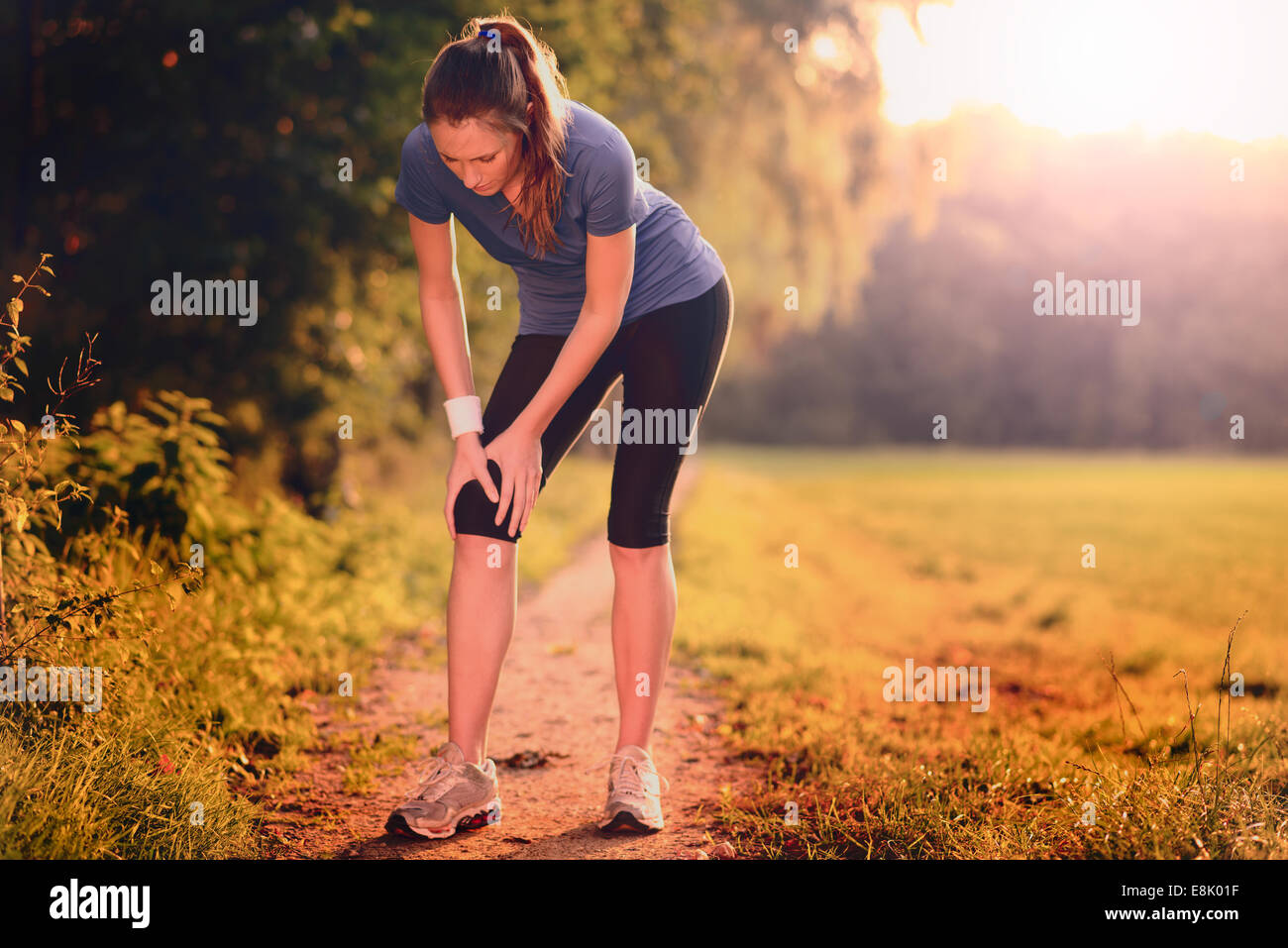 Young woman limbering up before training doing exercises to stretch her ...