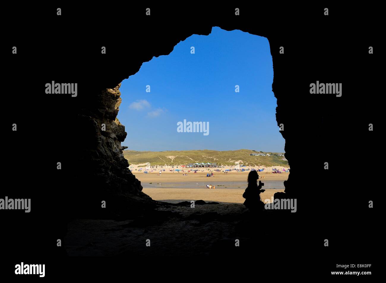 A silhouette of a female photographer taking a picture of a cave wall ...