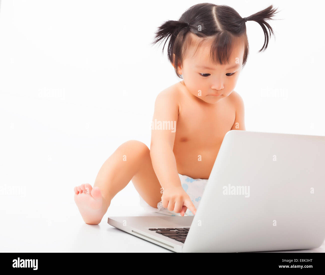 little child sitting playing on a laptop. isolated on white background ...