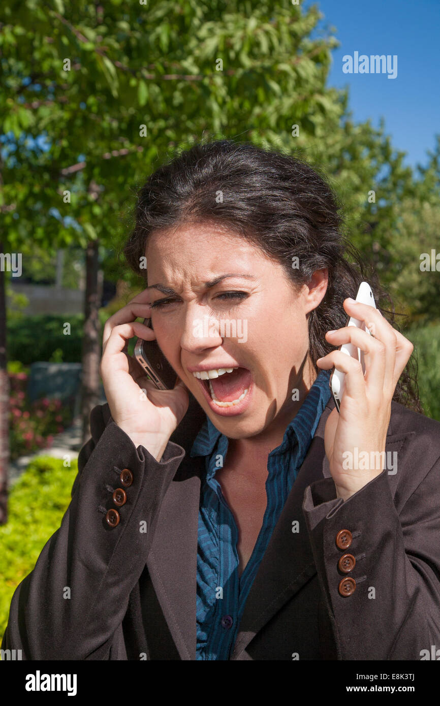 anger woman shouting with two mobiles in exterior Stock Photo - Alamy