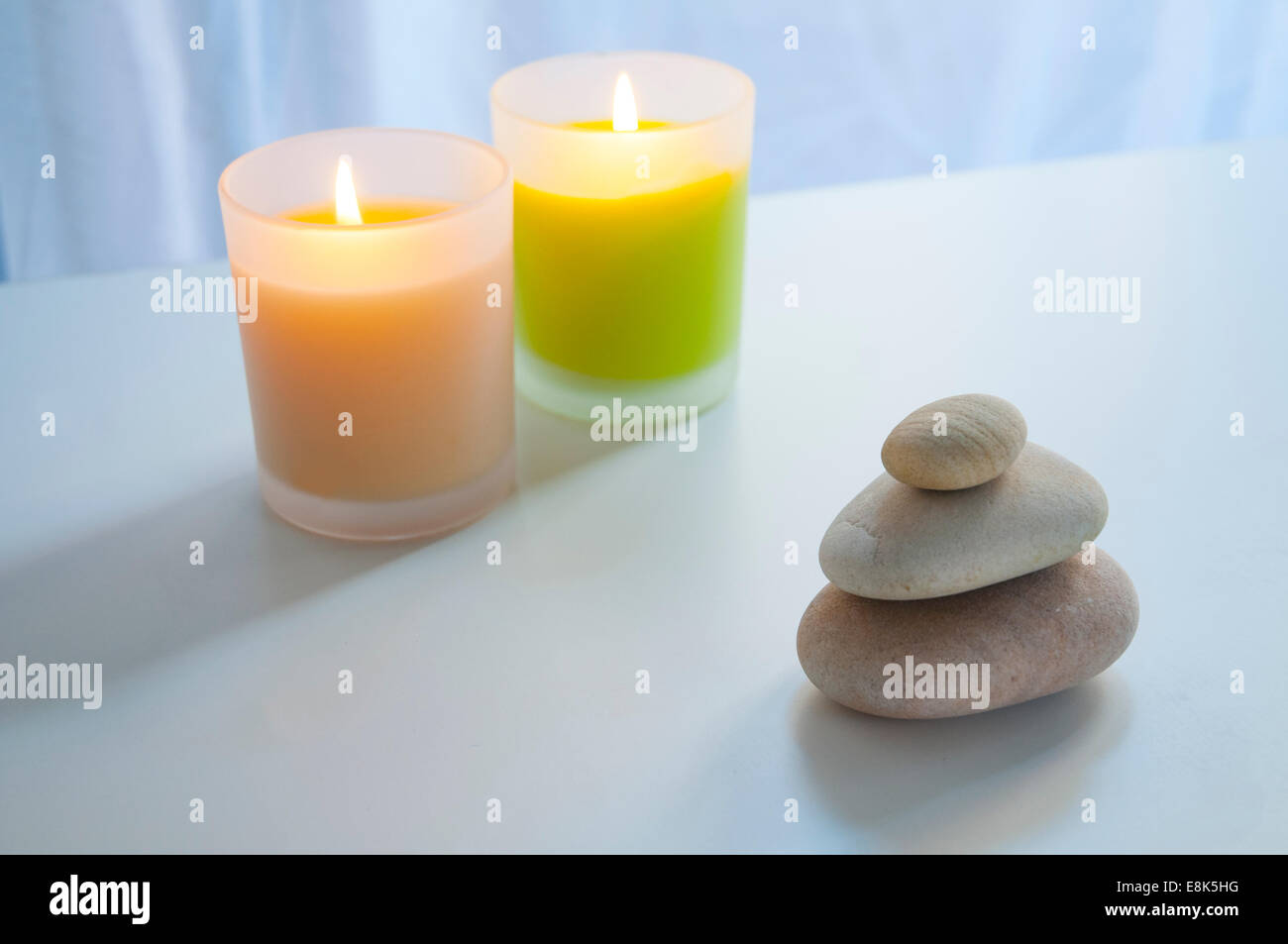 Stack of balanced stones and two lit up candles Stock Photo - Alamy
