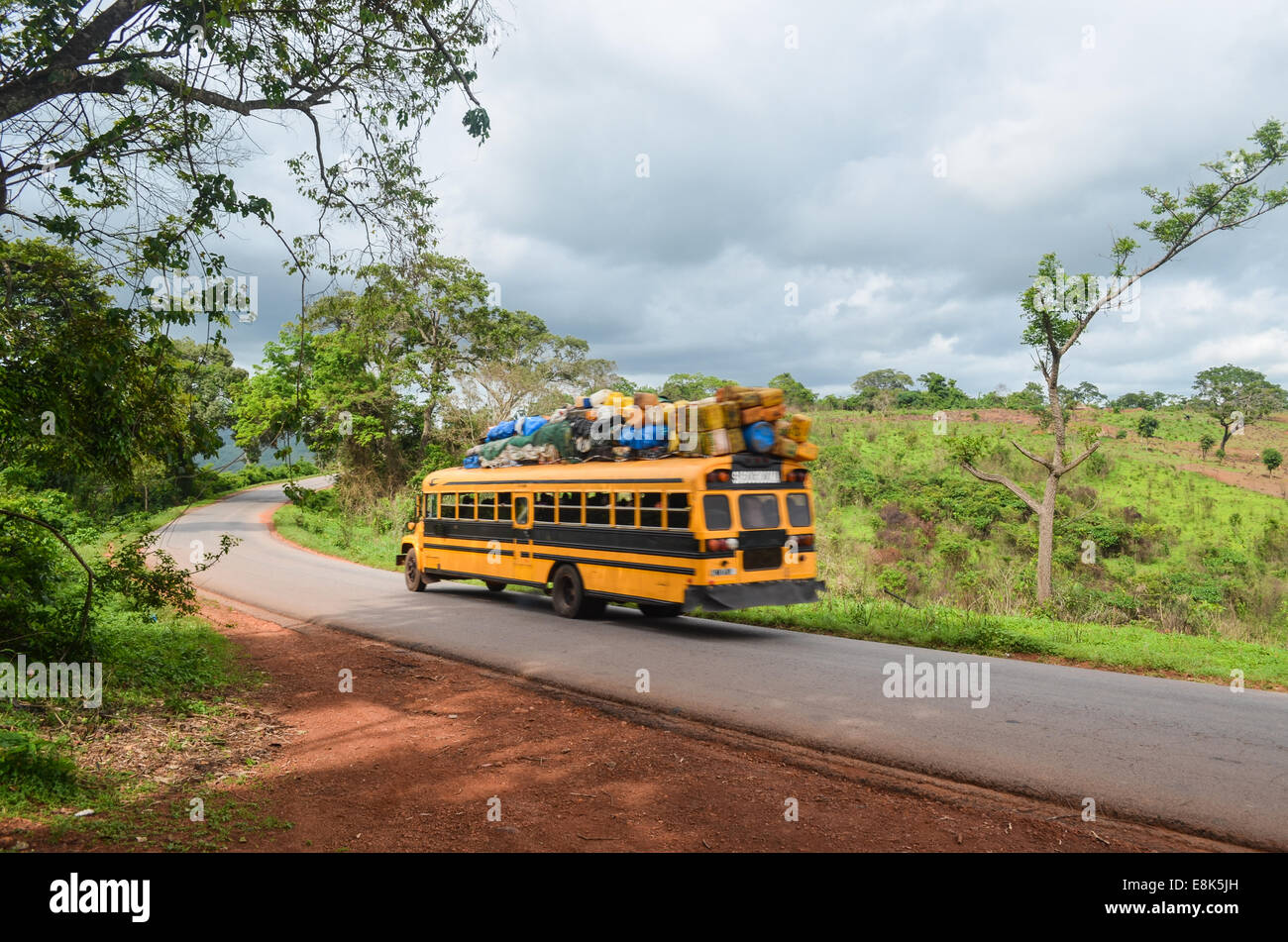 A yellow school bus driving in the hilly landscape of the Fouta Djalon ...