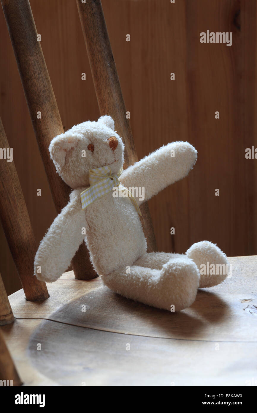 A small teddy bear is sitting on a wooden chair Stock Photo - Alamy