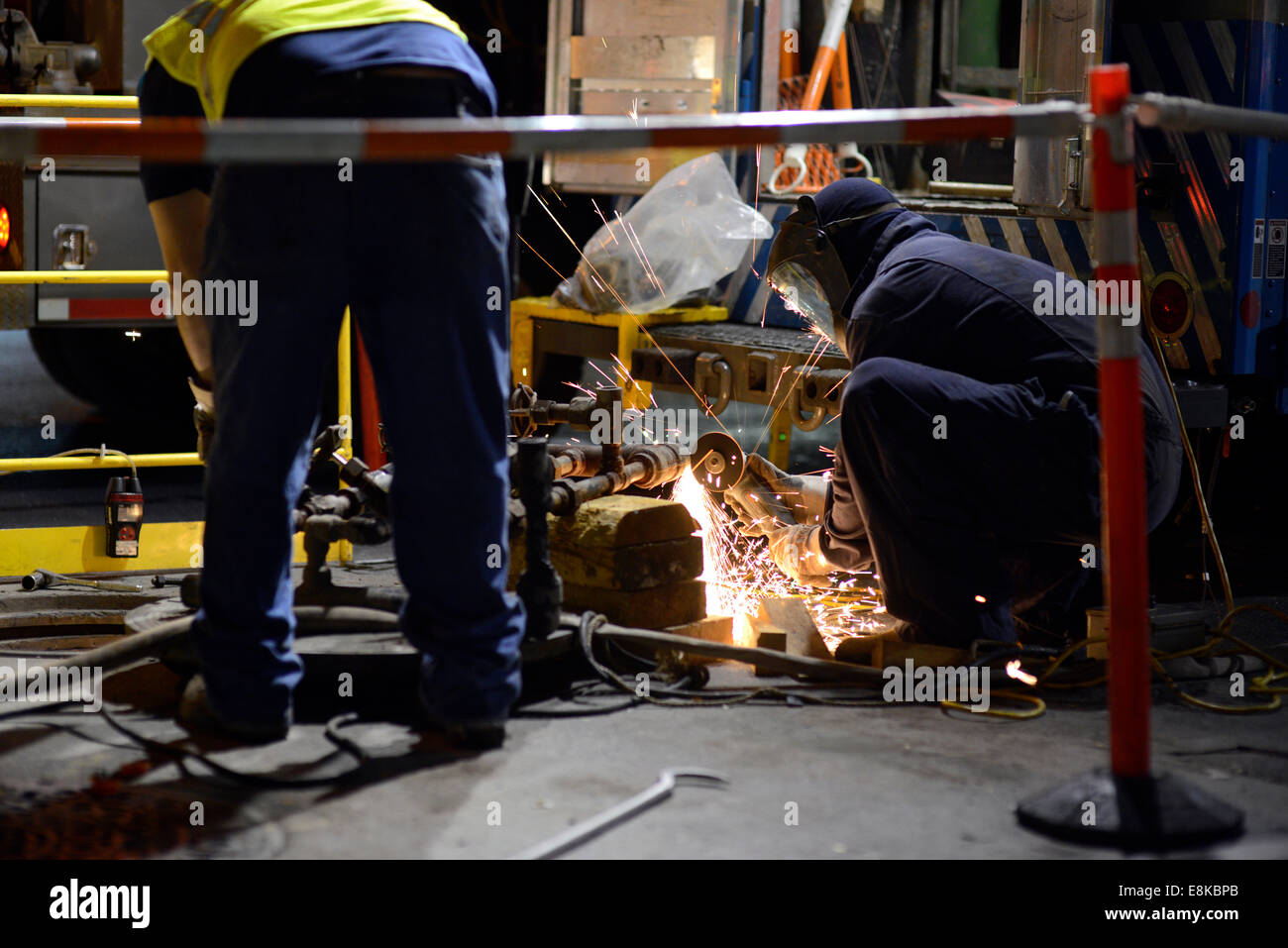 Sparks fly into a Con Edison worker's welding mask as he cuts a pipe on ...