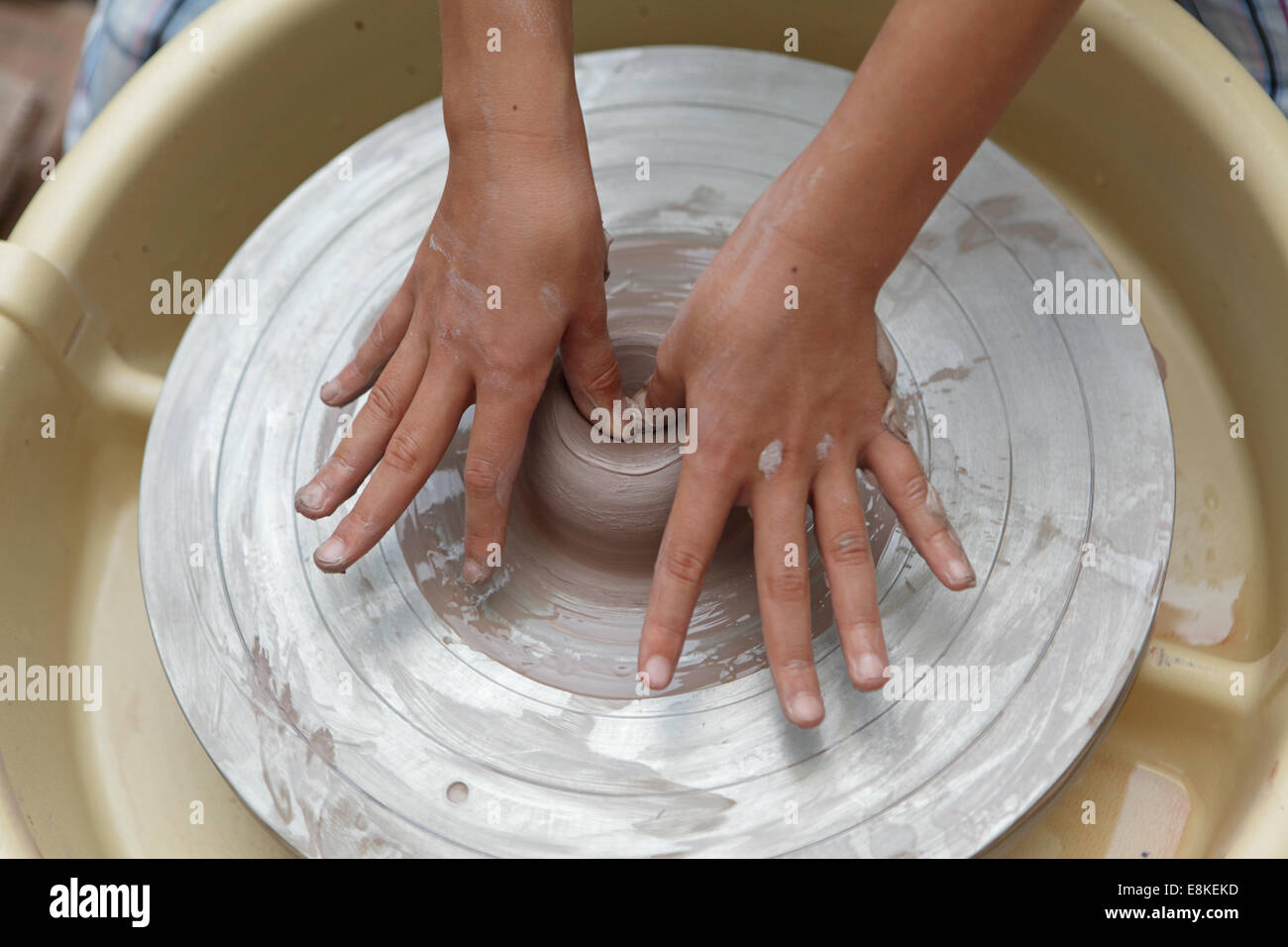 Young girl takes part in a pottery class learning how to use the wheel ...