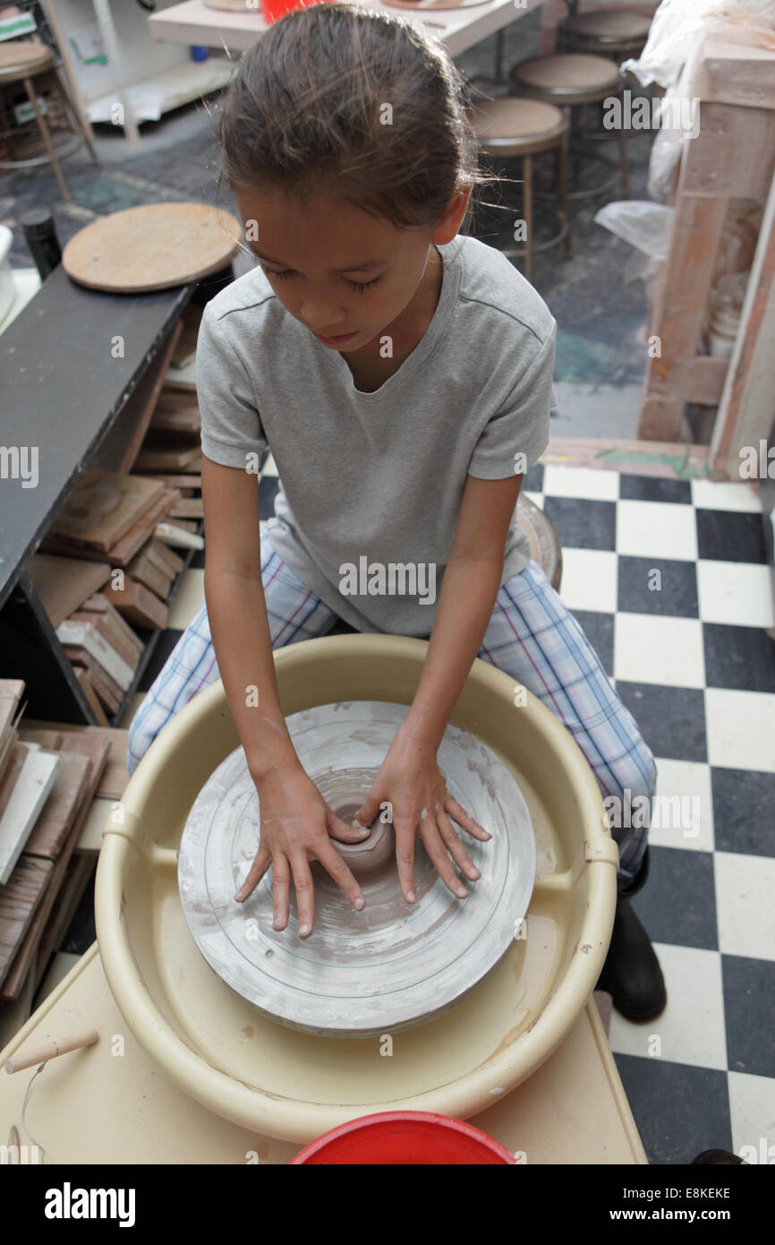 Young girl takes part in a pottery class learning how to use the wheel ...