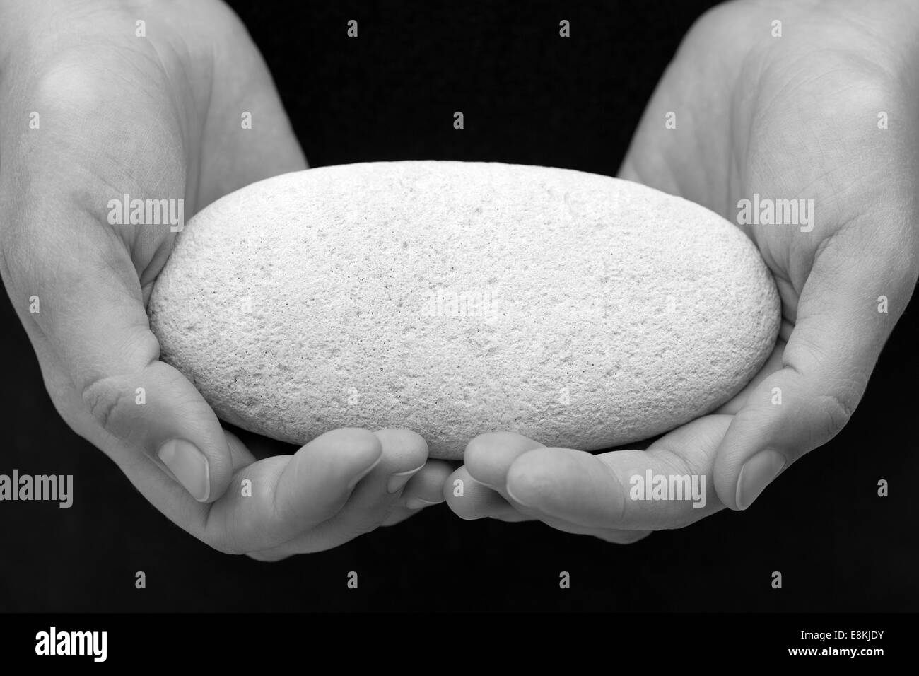 Woman's hands hold stone. Black and White Image. You can add your text ...