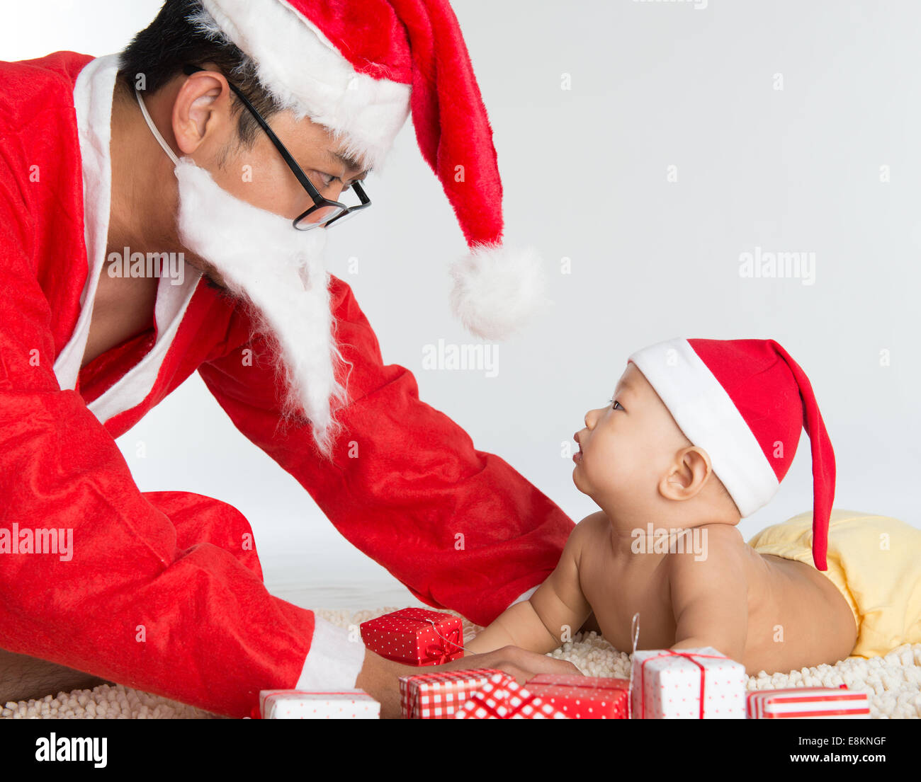 Asian santa claus with baby boy, many Christmas presents on floor Stock ...