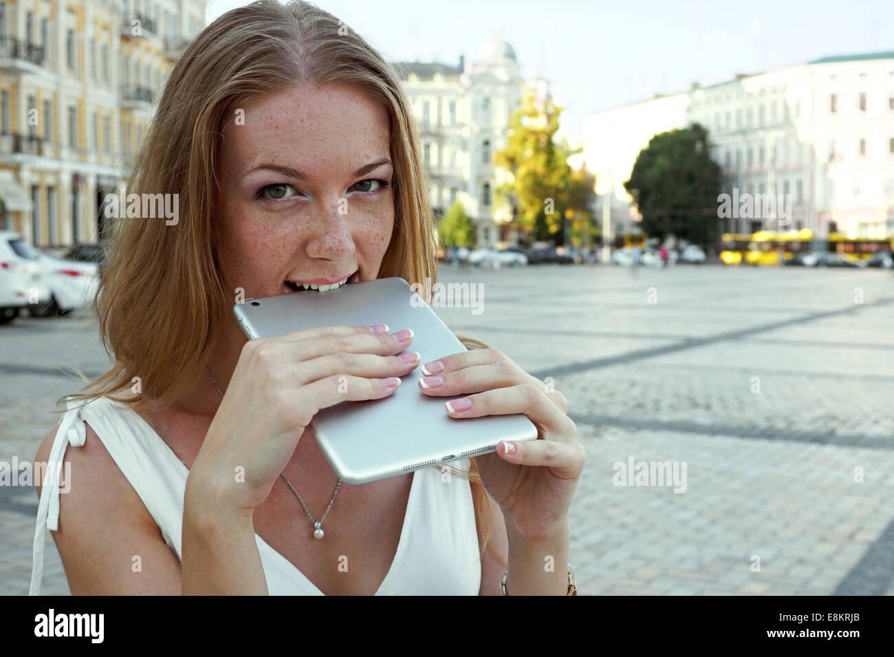 Young woman bite a tablet staying outdoor Stock Photo - Alamy