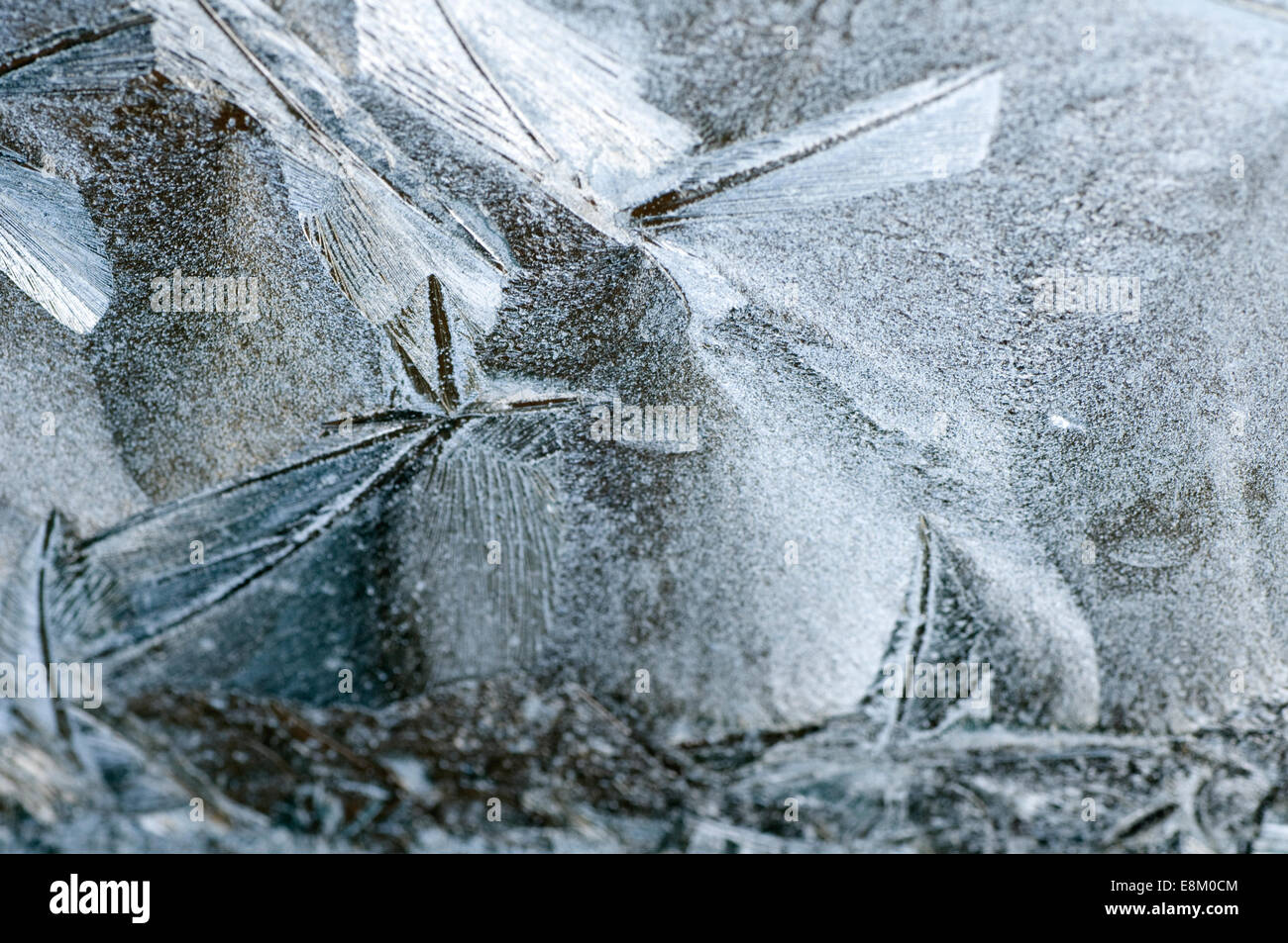 Ice frost etched on vehicle window screen with pale sun bleached behind ...