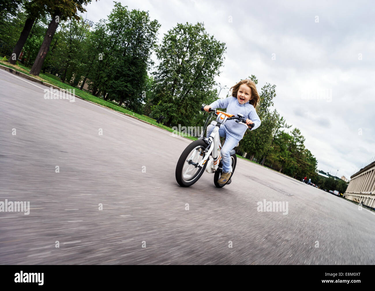 Cute little girl riding fast by bicycle in public park Stock Photo - Alamy