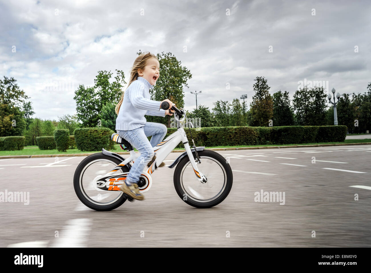 Cute little girl riding fast by bicycle in public park Stock Photo - Alamy