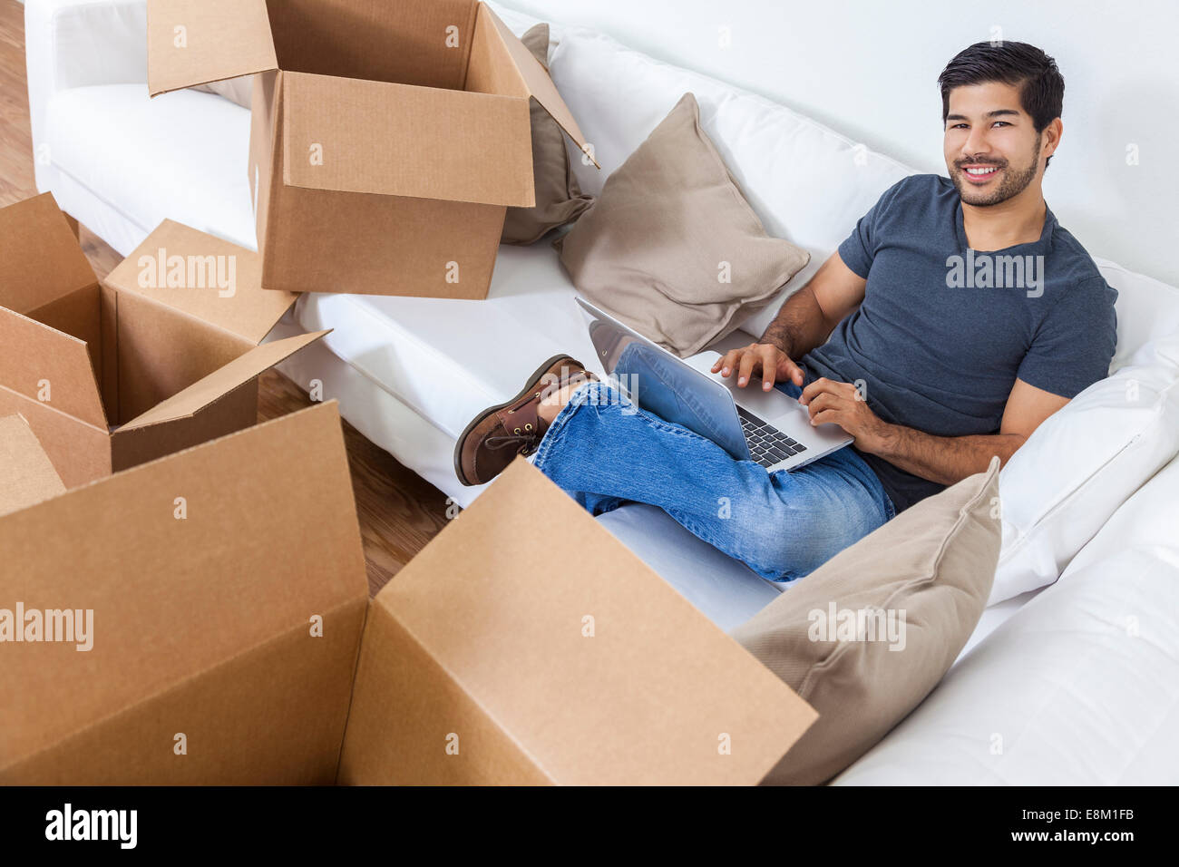 Asian Chinese Korean man packing or unpacking boxes using a laptop ...