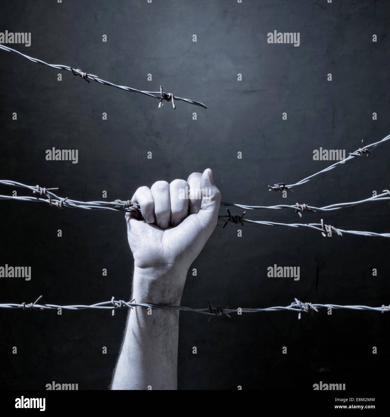 hand behind barbed wire with dark background Stock Photo - Alamy
