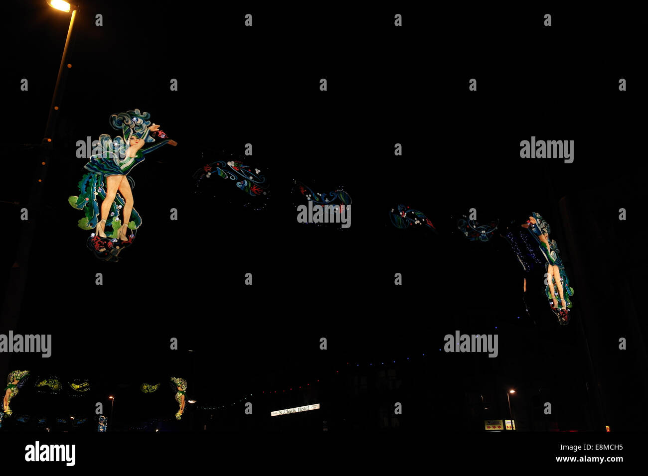 Night view four illuminated burlesque beauties attached lamp-posts ...