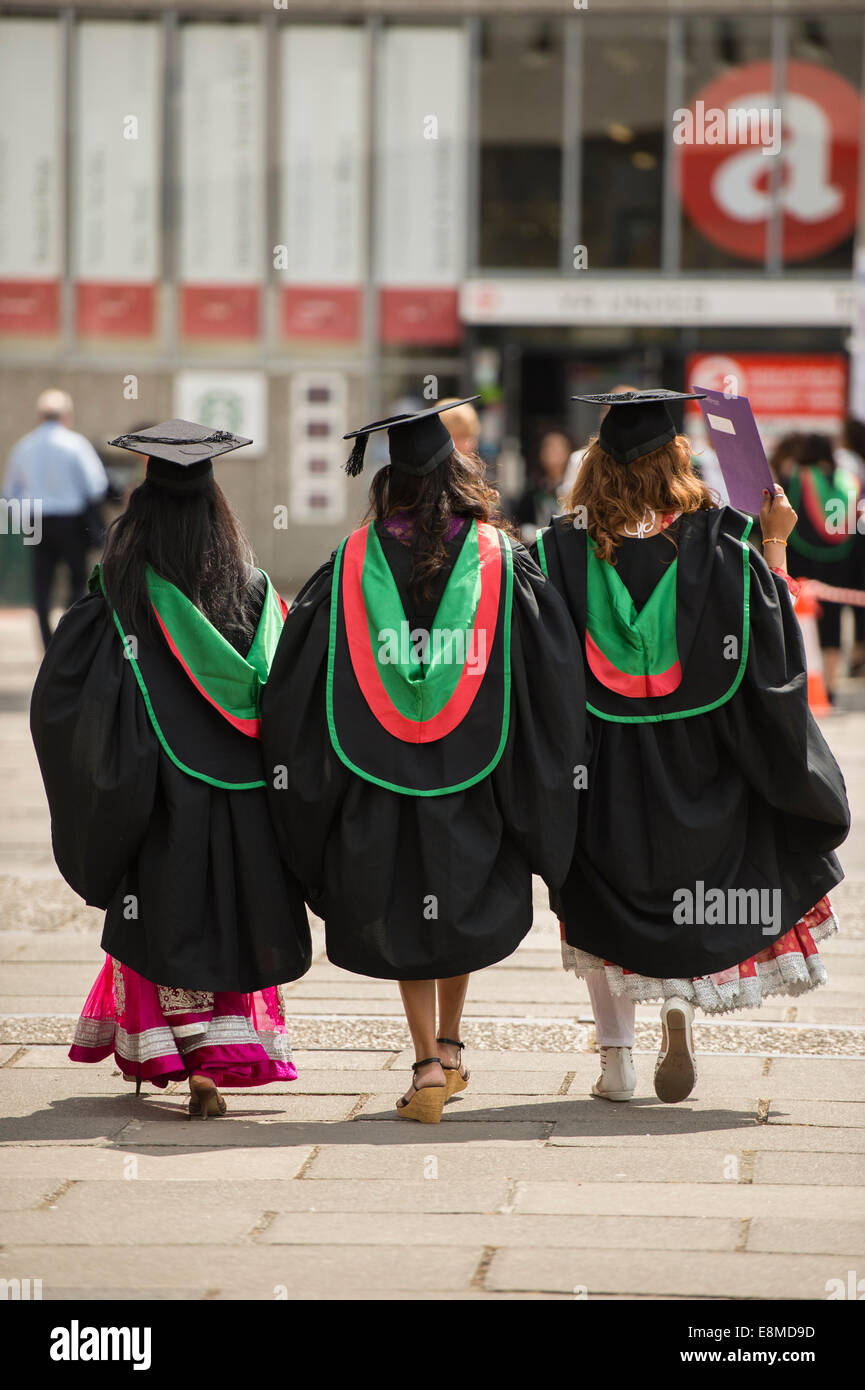 Three women students in their traditional gowns and mortar boards ...
