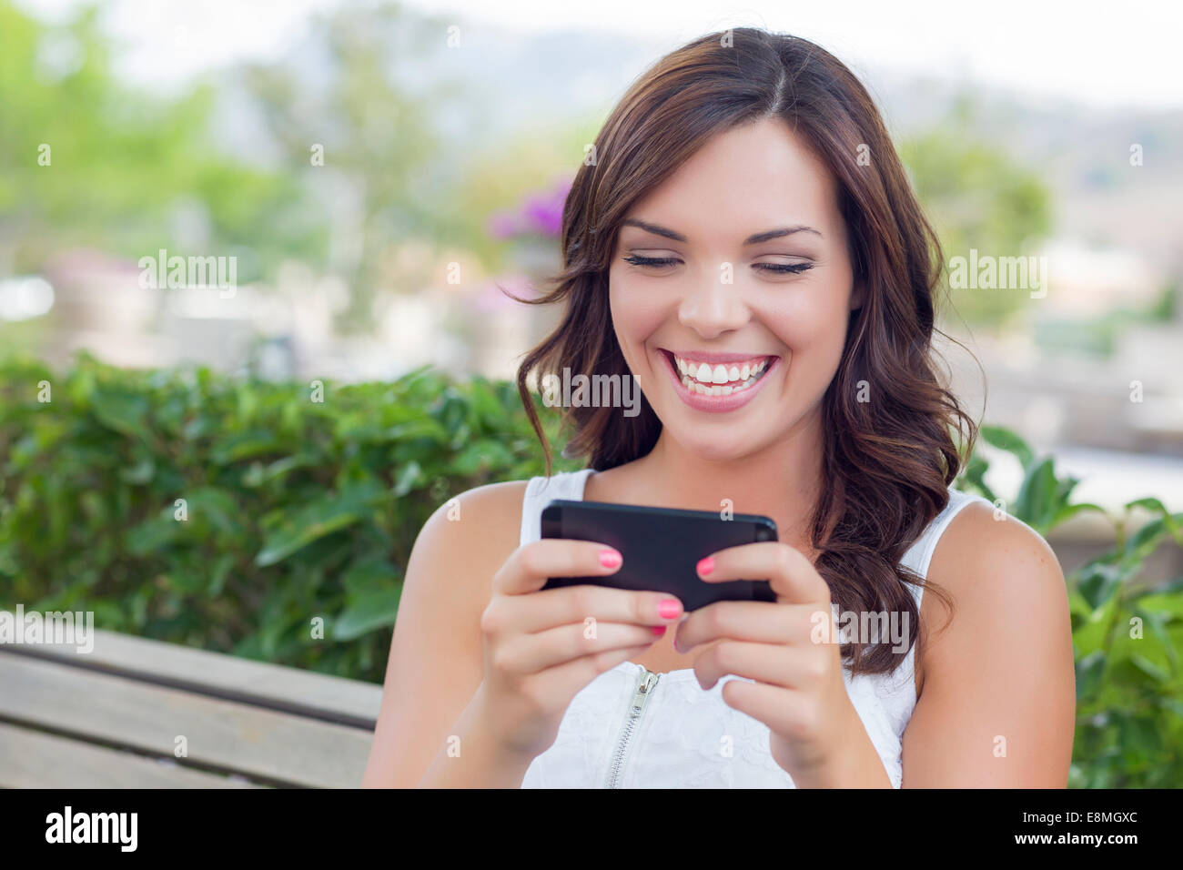 Attractive Smiling Young Adult Female Texting on Cell Phone Outdoors on ...