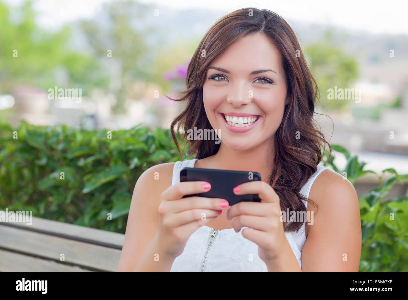 Attractive Smiling Young Adult Female Texting on Cell Phone Outdoors on ...