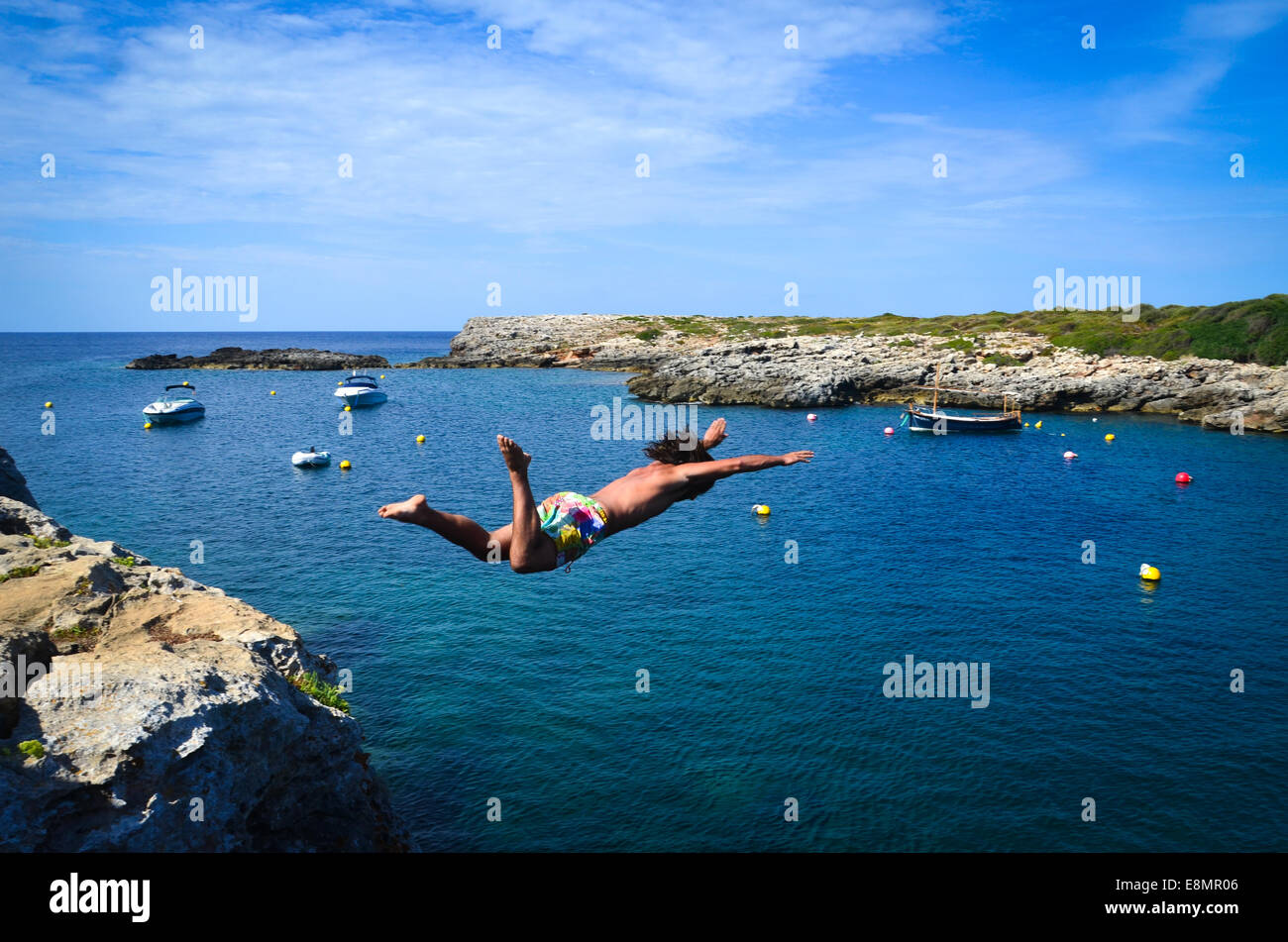 Cliff diving in the habour of the traditional small town of Binibequer ...