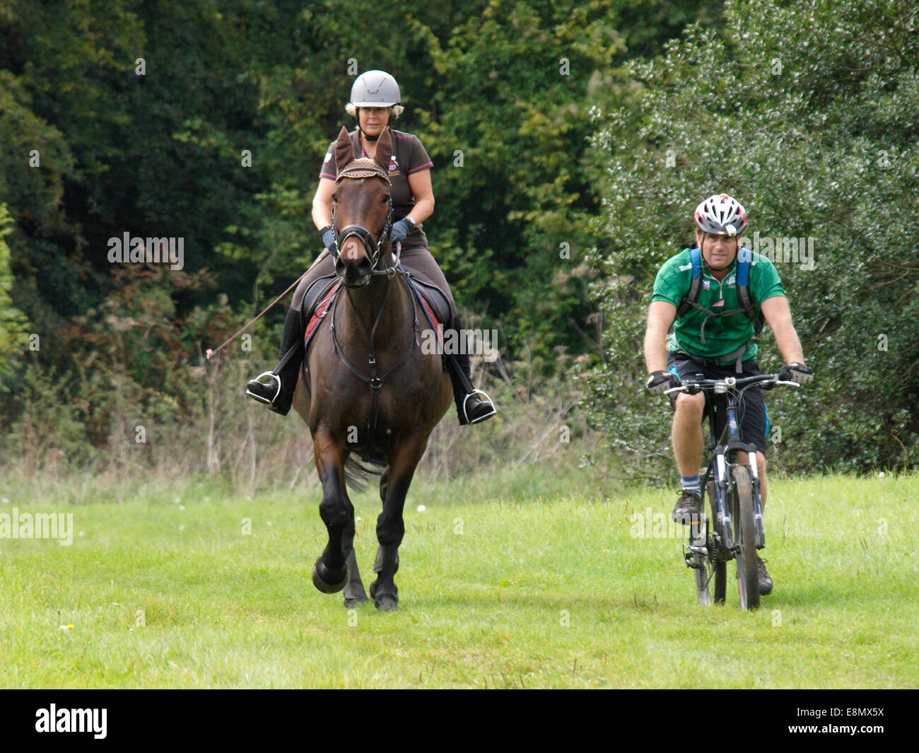 Woman on horse riding with man on a mountain bike, Chettle, Dorset, UK ...
