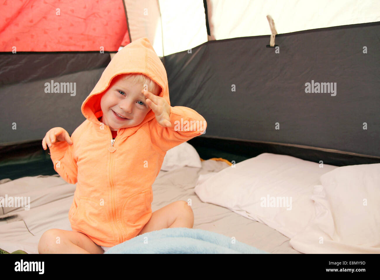 A happy young boy child is waking up in a tent after spending the night ...