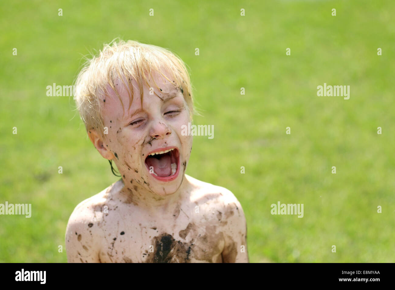 A little boy child is happily screaming as he is playing outside ...