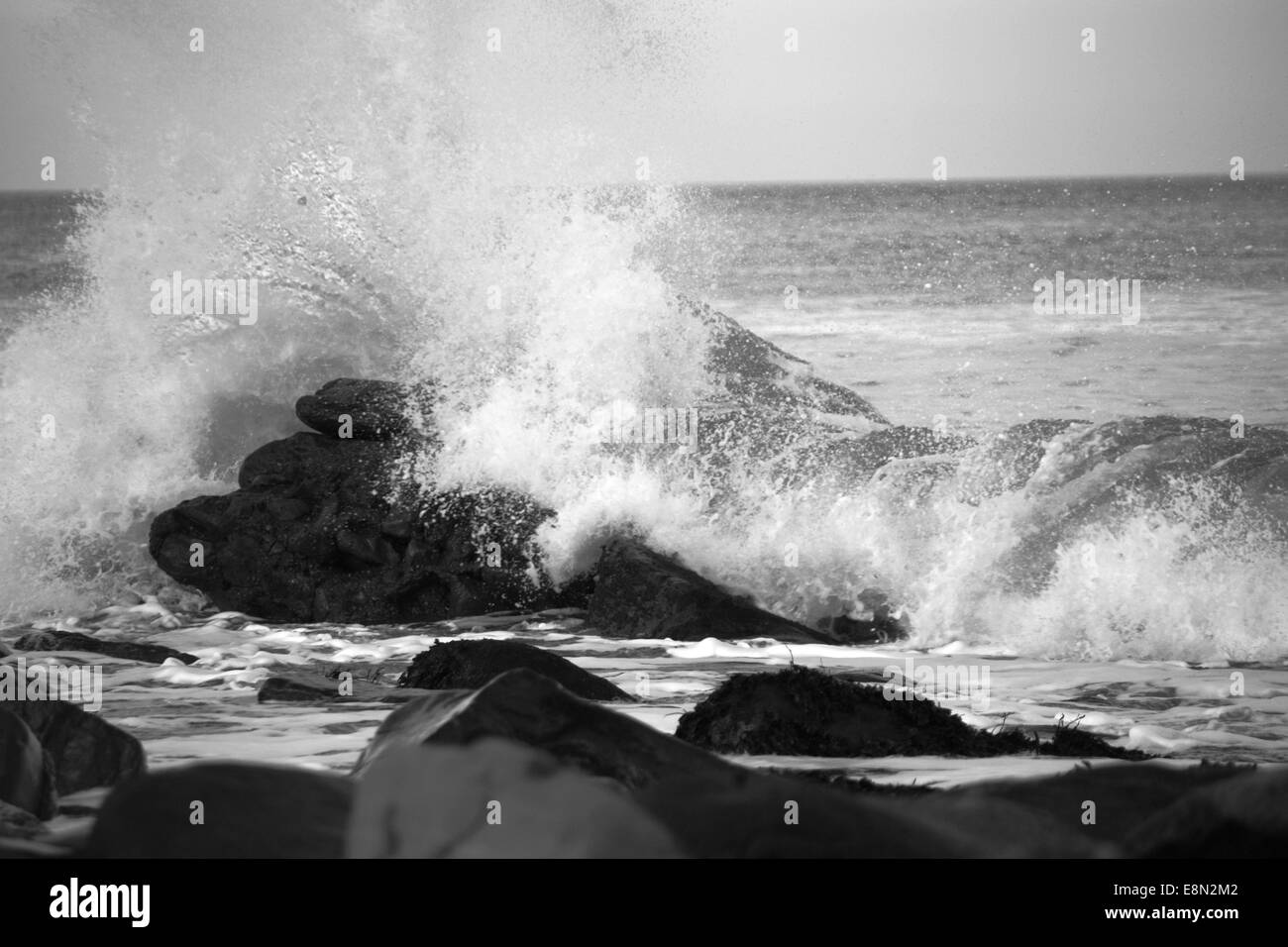 waves crashing over rocks on the sea shore in black and white Stock ...