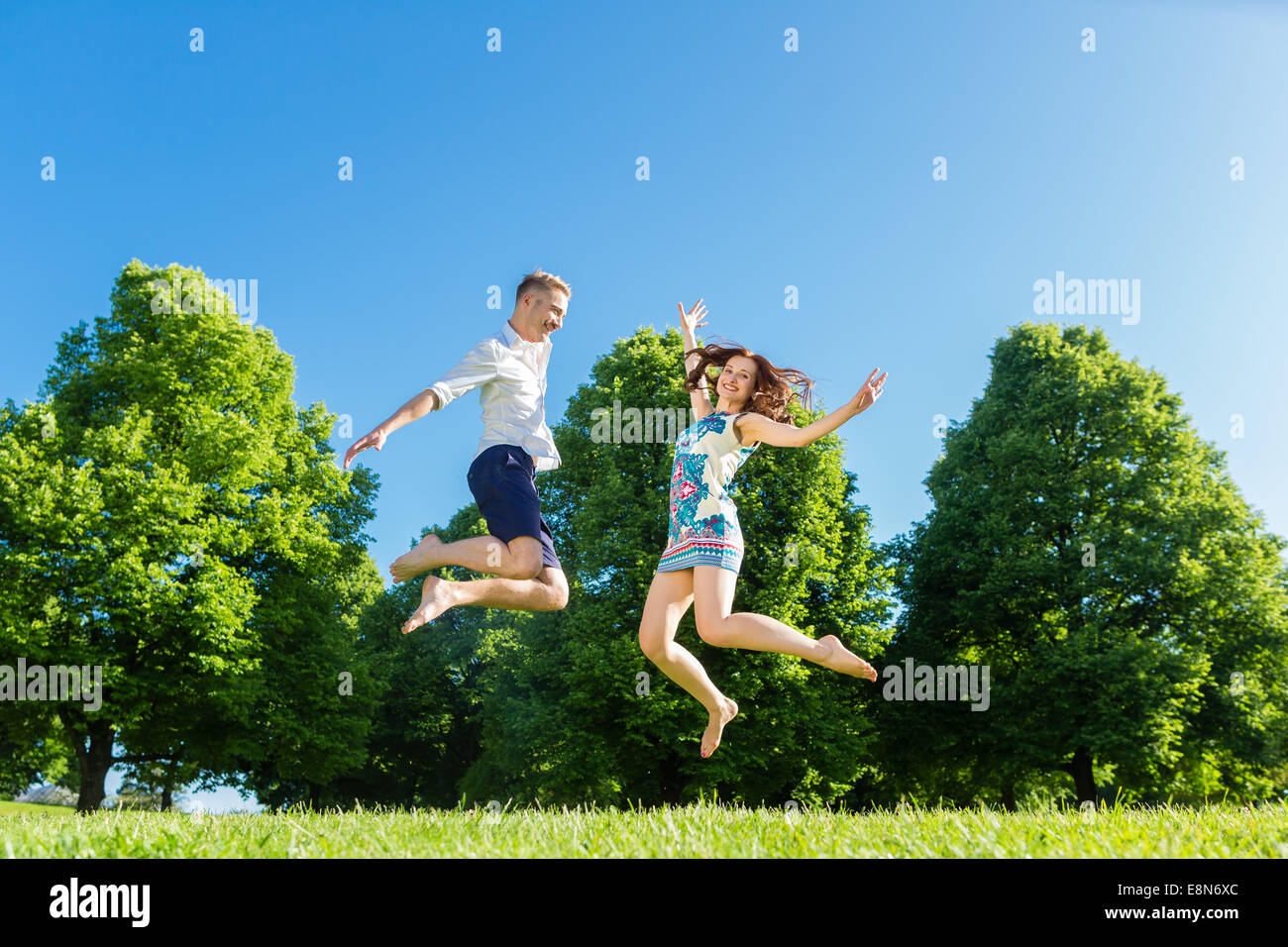 Couple in love jumping on park lawn Stock Photo - Alamy