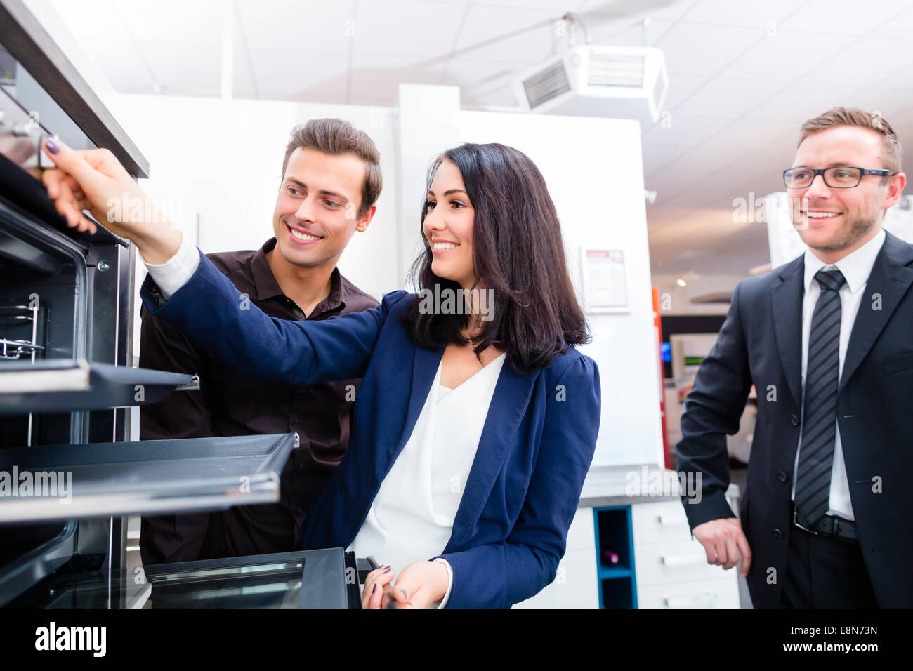 Woman picking oven for domestic kitchen in studio or furniture store ...