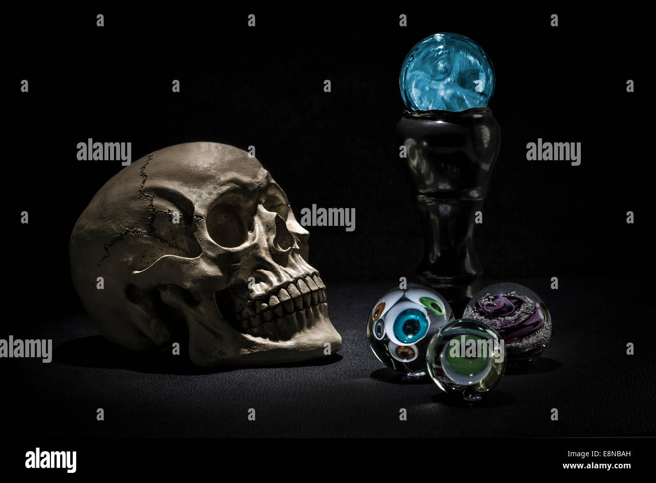 Dark and shadowy human skull in a pool of light. Crystal balls with ...